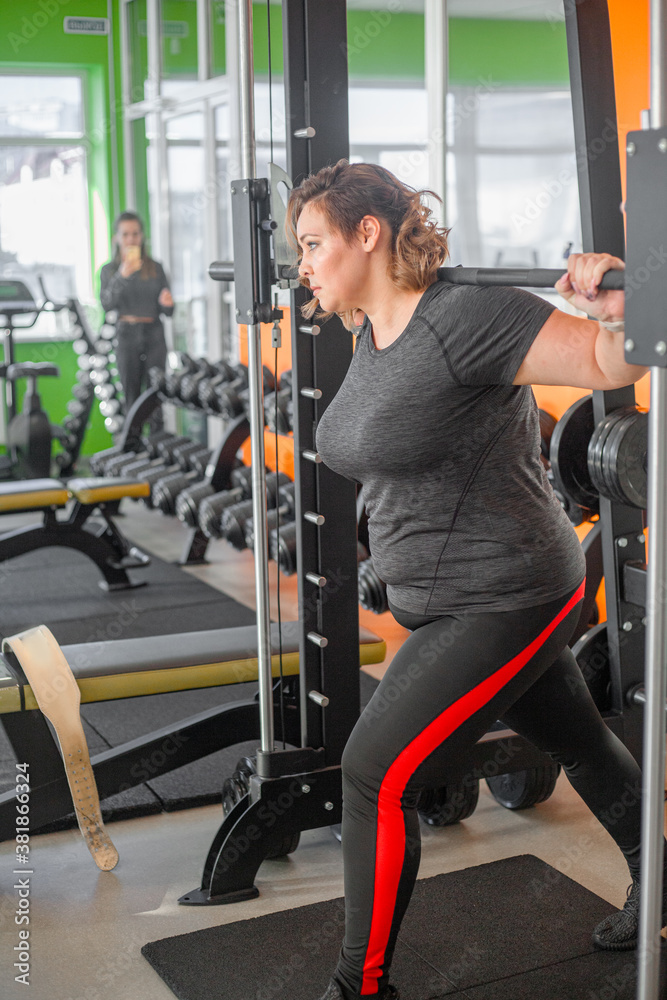 Fat woman fights overweight in the gym, doing heavy fitness exercises ...