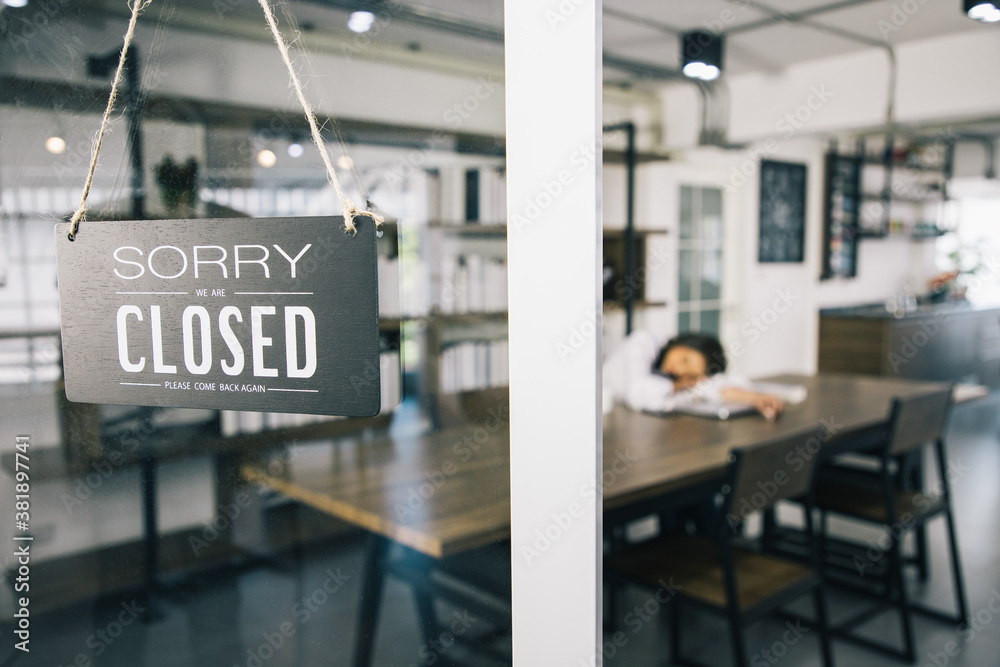 Closed sign board through the glass of store window of cafe because due ...