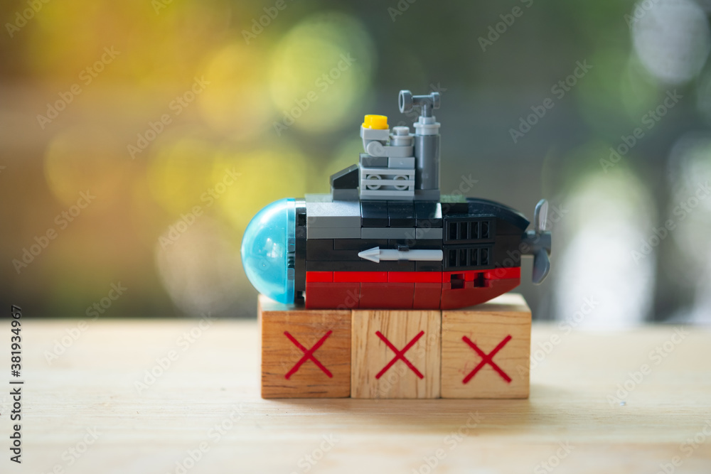 Plastic submarine toy placed on X symbol wooden blocks and natural ...
