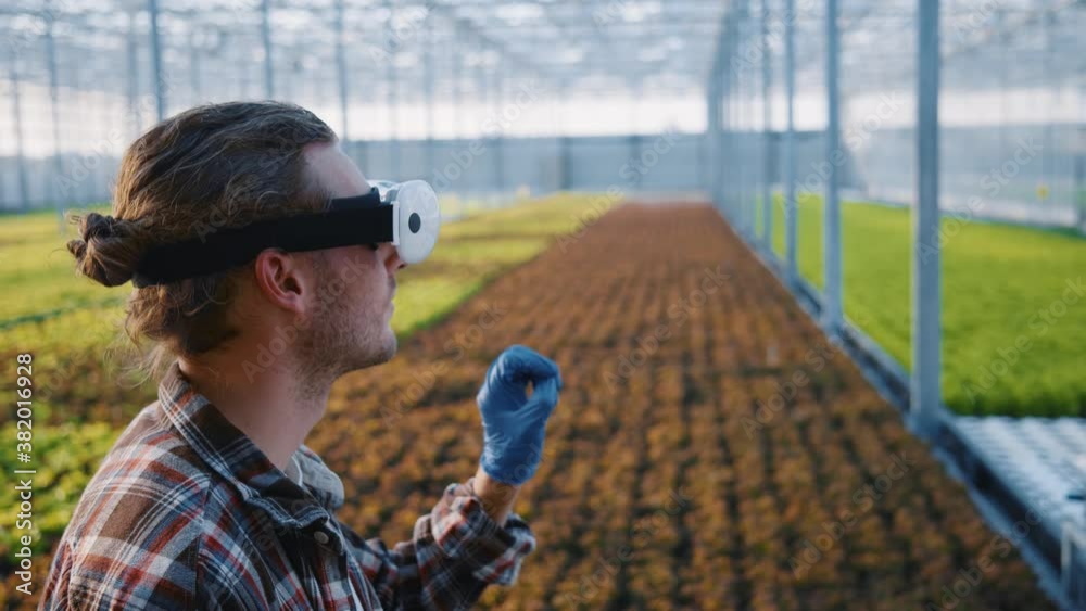 Stockvideo Greenhouse young caucasian worker using VR technology to ...