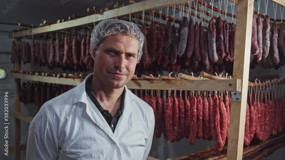 Handsome man butcher meat specialist worker standing at smokehouse on ...
