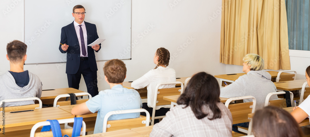 Portrait of adult male teacher conducting lesson for teenage ...