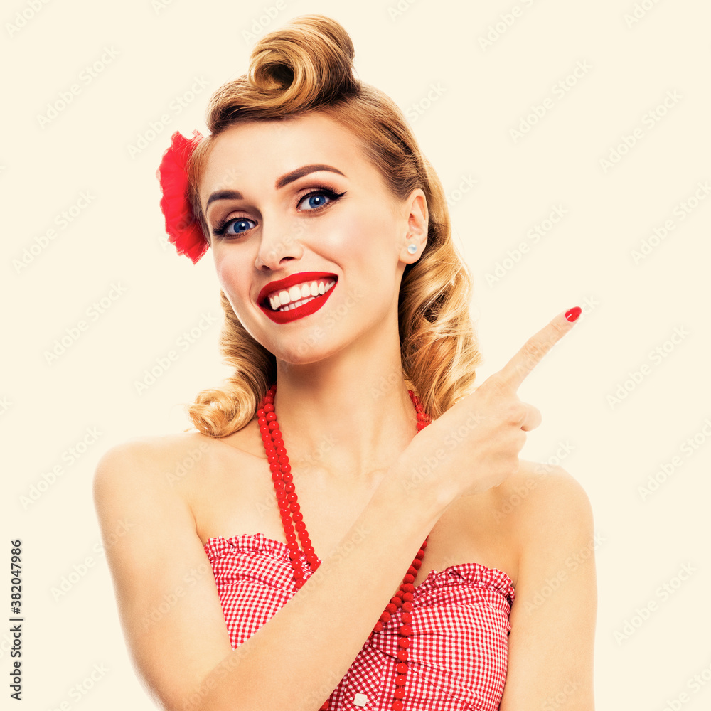 Happy smiling beautiful blond woman pointing at something. Pinup girl ...