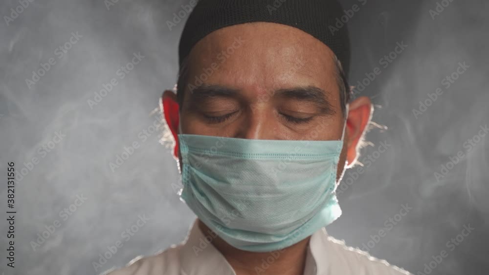 Close up shot of Muslim man in medical mask starting Salah or prayer by ...