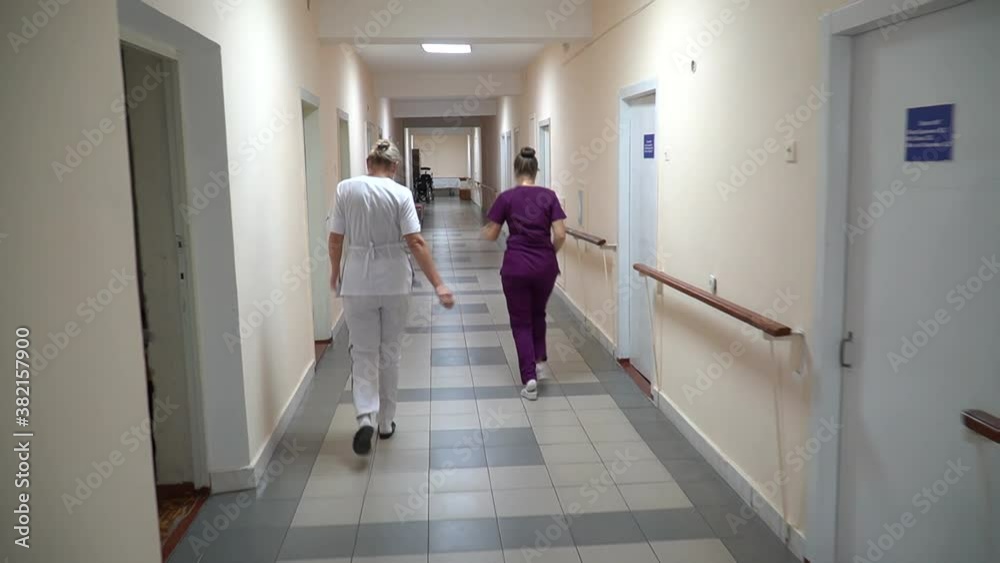 a nurse running to a patient's call along a long hospital corridor ...