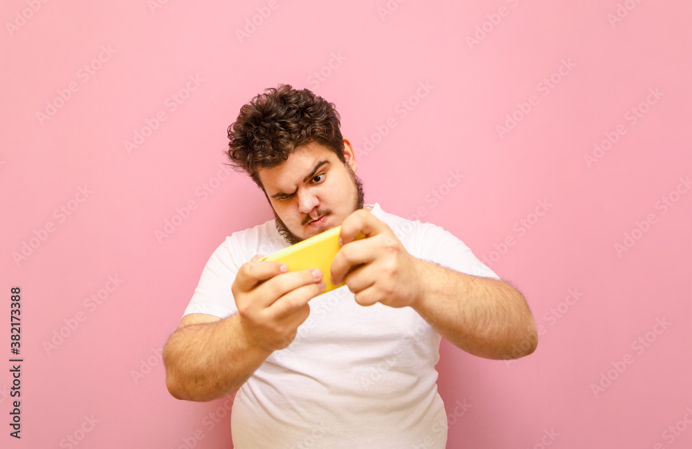 Portrait funny overweight gamer standing on a pink background and ...