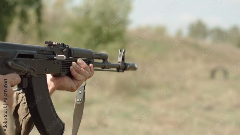 Armed man shooting a assault rifle Kalashnikov at target. Shot out ...