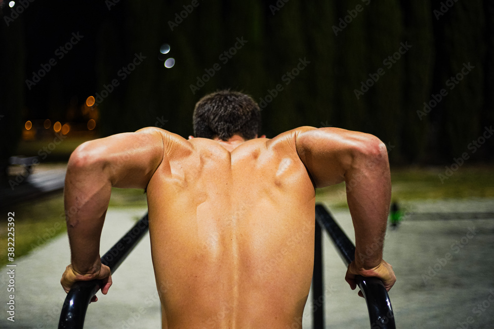 Young shirtless guy training at night street workout. Doing dips. Stock ...