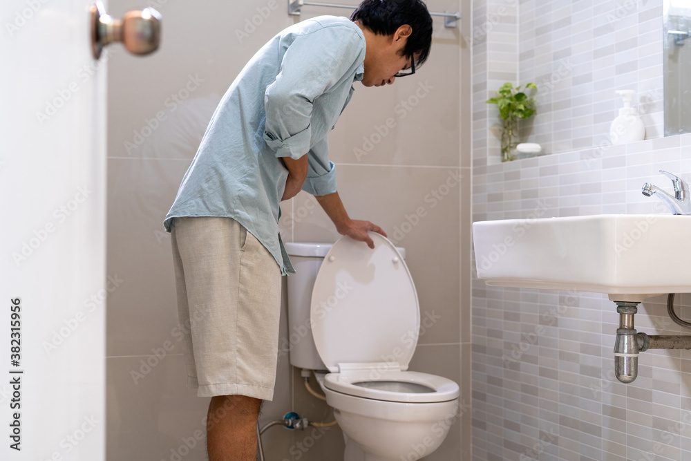 An Asian man in front of the toilet has severe abdominal pain. The man ...