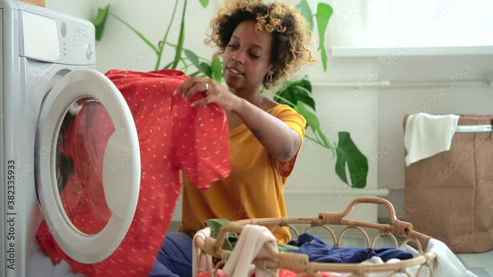 african american woman put dirty laundry in washing machine at home ...