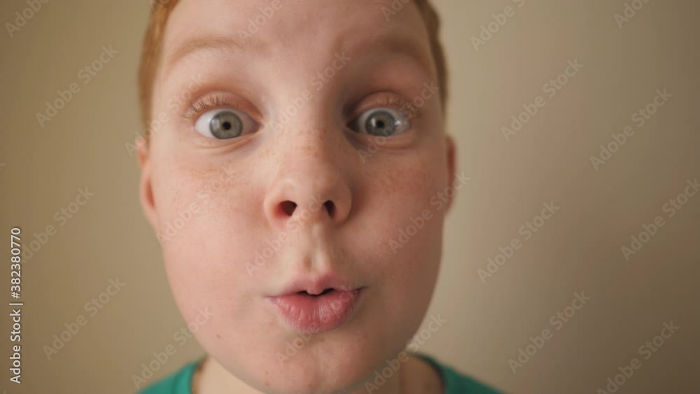 Little red-haired boy looking into camera with wow expression indoor ...