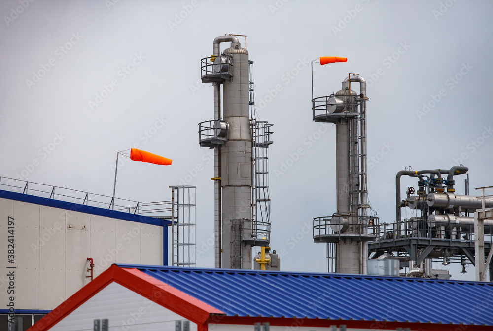 Distillation towers with orange weather vanes on grey sky background ...