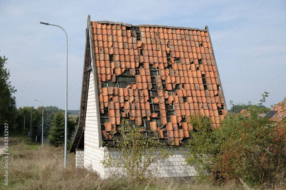 A house with a high sloping red tiled roof. Destroyed roof with falling ...