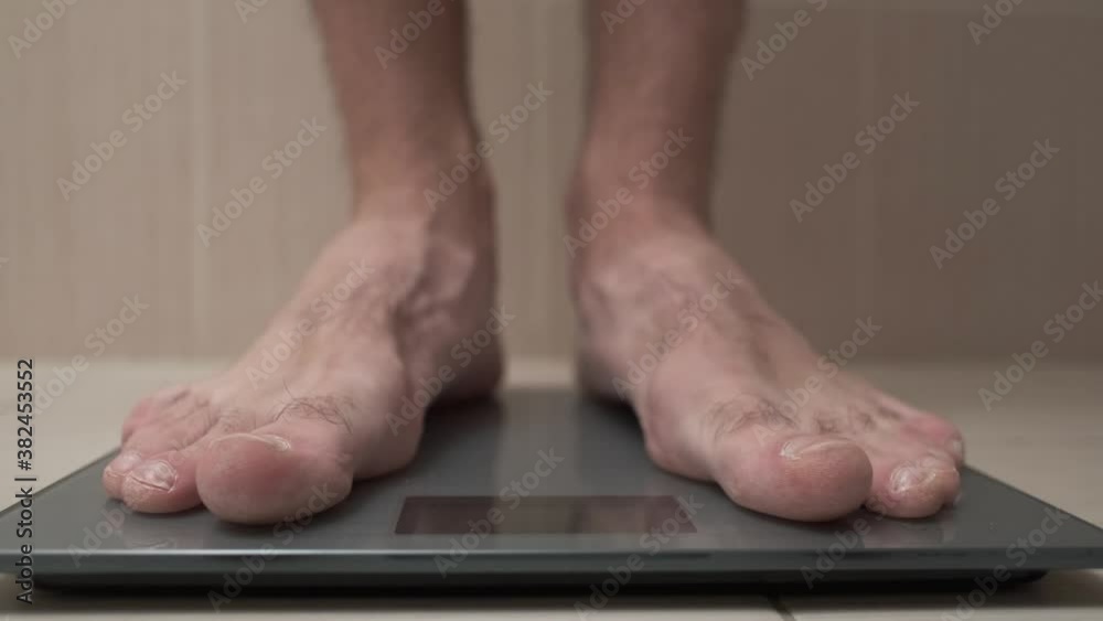 Barefoot man steps on electronic scales and measure weight, close-up ...