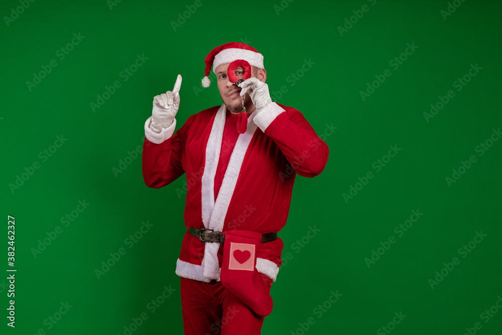 Male actor in a costume of Santa Claus holds red fur handcuffs and a ...