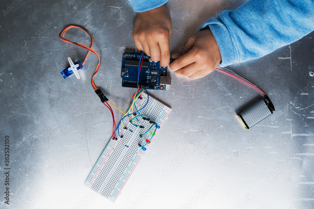 Boy connecting electronical parts to create his first little robot ...