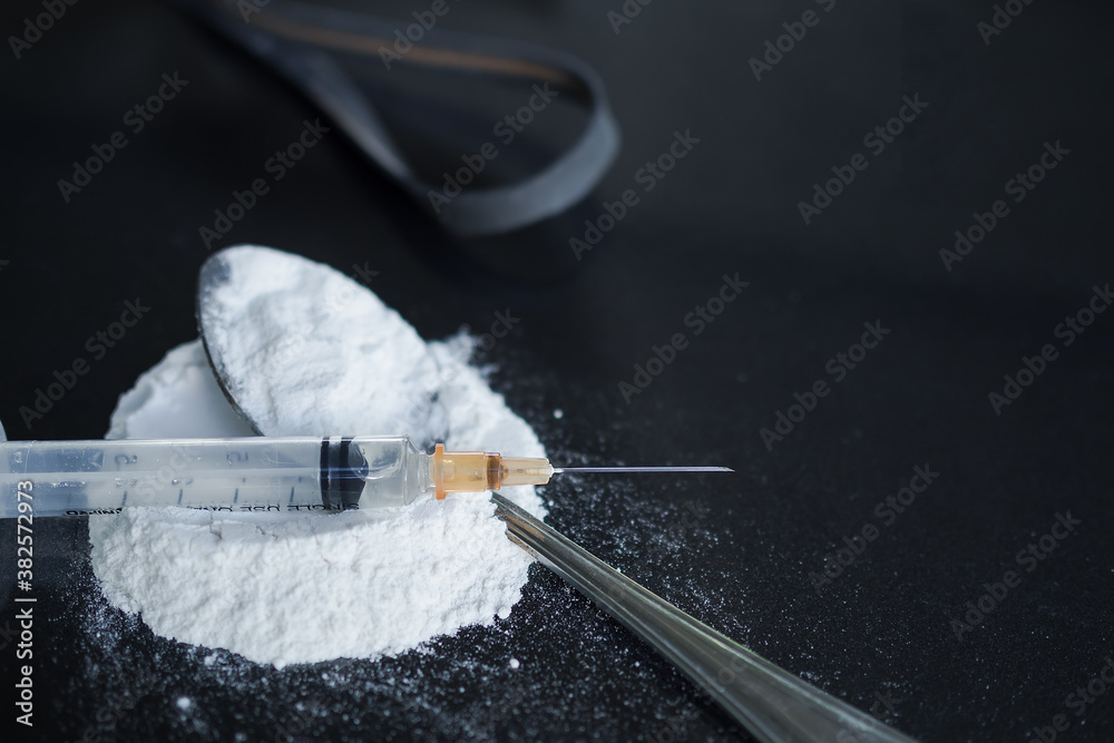 Morphine in syringe and powder morphine on spoon with black rubber band ...