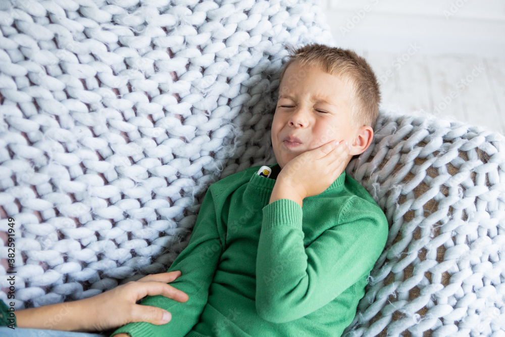 Bol'nyy mal'chik s termometrom lezhal v posteli i mat' ruki prinimaya temperaturu. Mama ...