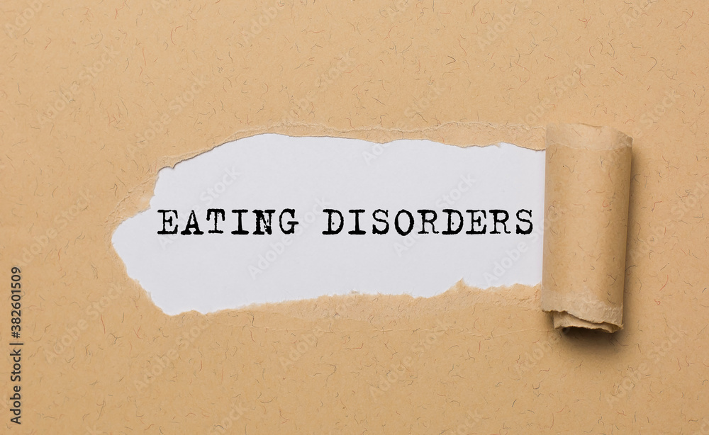 The text Eating Disorders, appearing behind torn paper. Medical concept ...