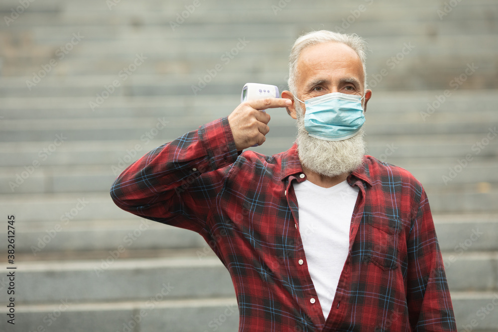 Bearded senior man measuring himself infrared thermometer a healthy ...