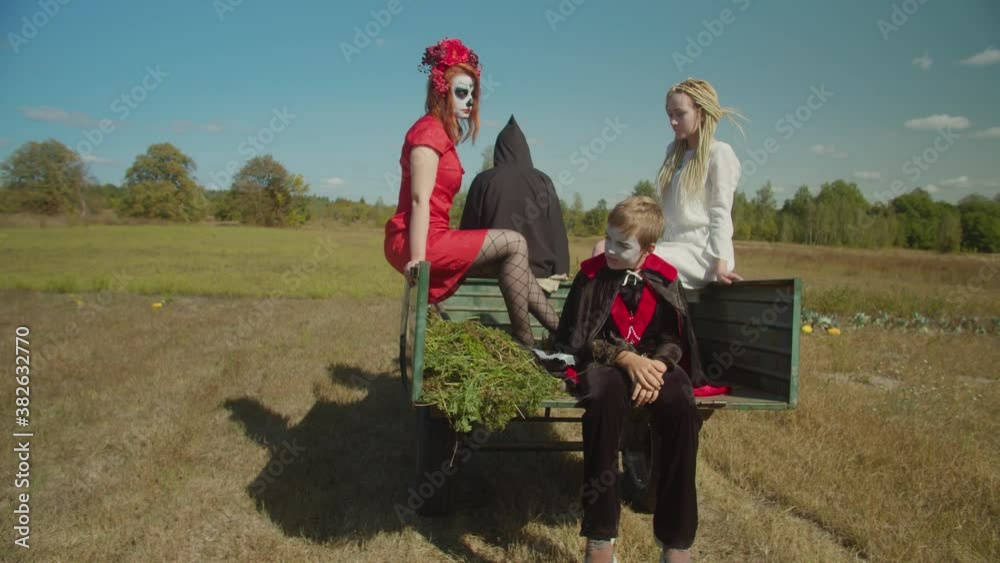 Dark angel of death in black shroud driving mini tractor with people ...