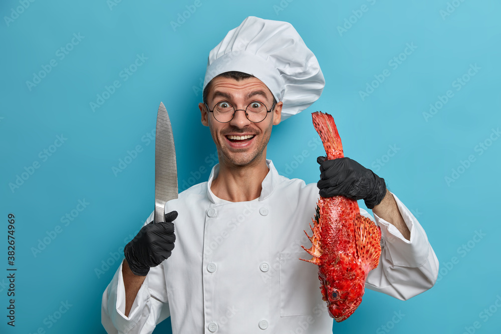 Happy professional chef cook dressed in white outfit holds sharp knife ...