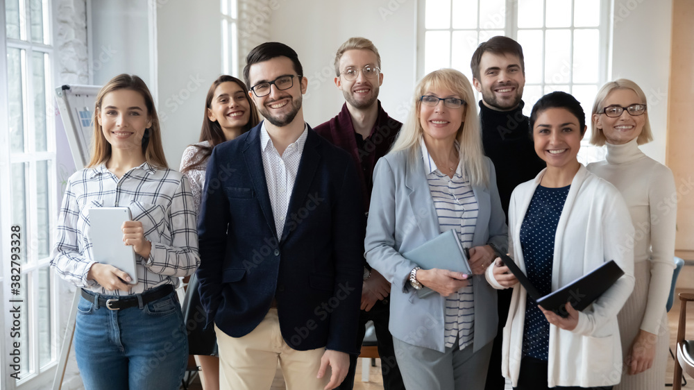 Portrait of smiling diverse team posing together in office show unity ...