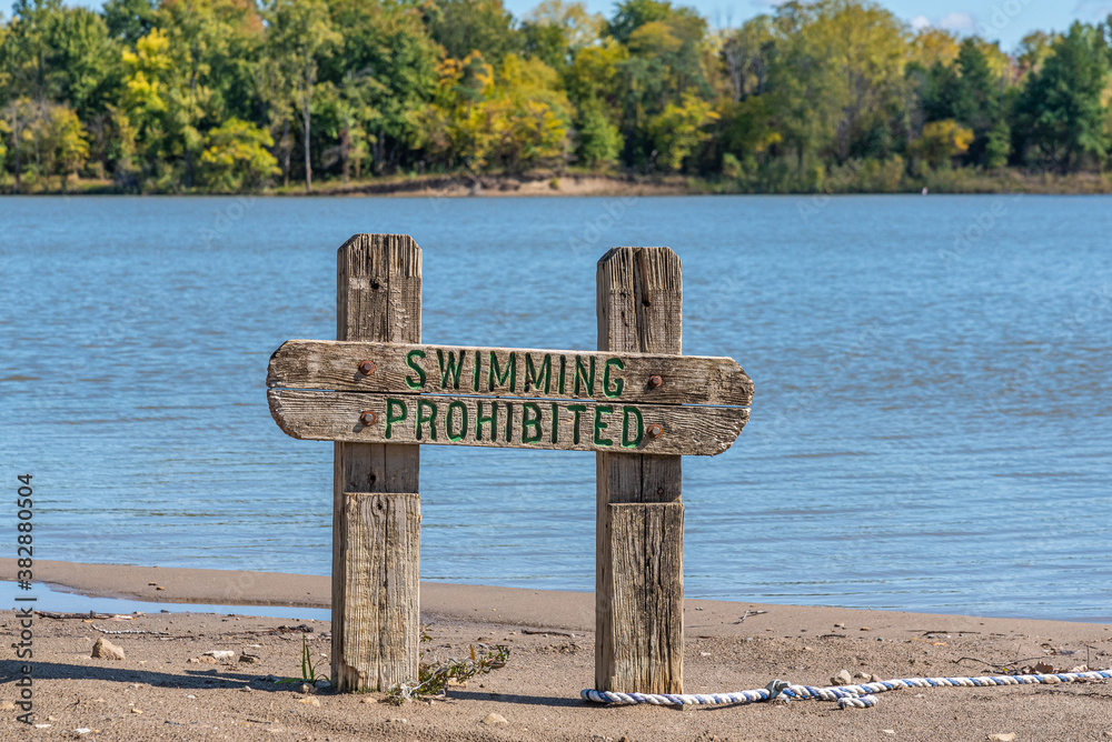 Swimming Prohibited wooden sign on beach near beautiful calm blue water ...