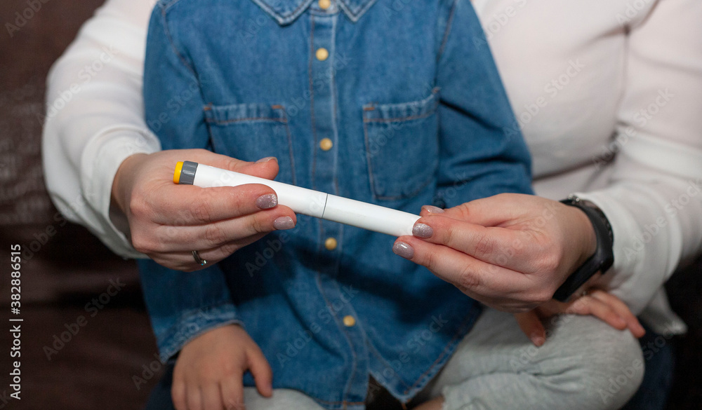 Female hands give an injection to a small child. Insulin syringe. A ...