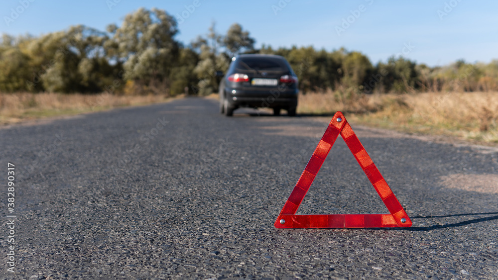 Red warning triangle on the road in front of a broken car. Breakdown of ...