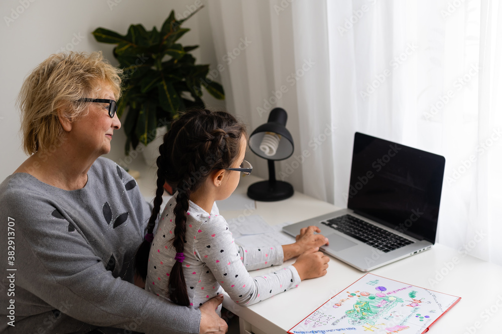 Cute and happy little girl child using laptop computer with her grandma ...