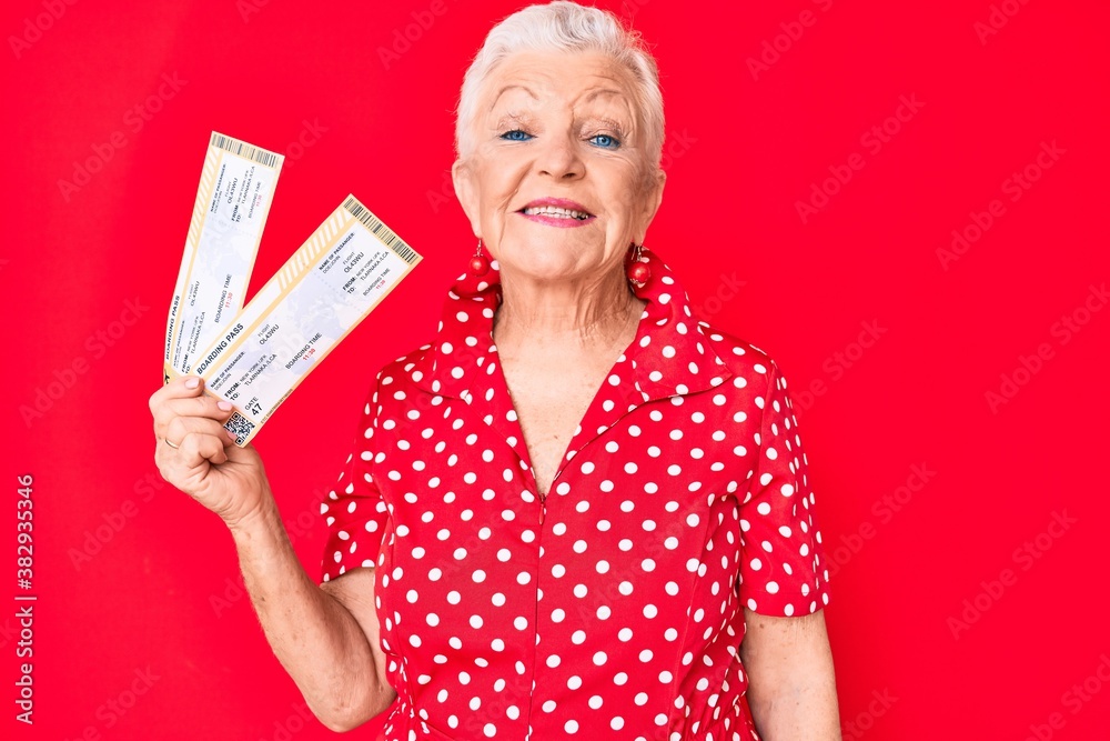 Senior beautiful woman with blue eyes and grey hair holding boarding ...
