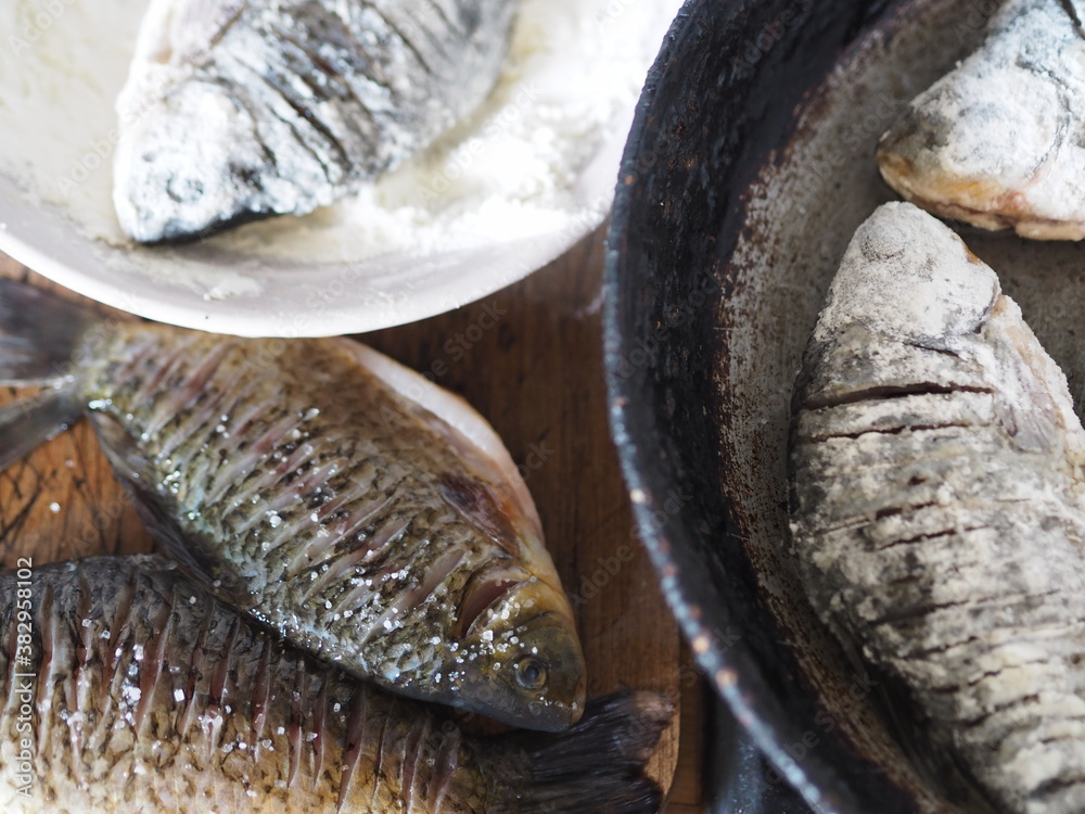 The process of frying river fish crucian carp in a pan on a kitchen ...