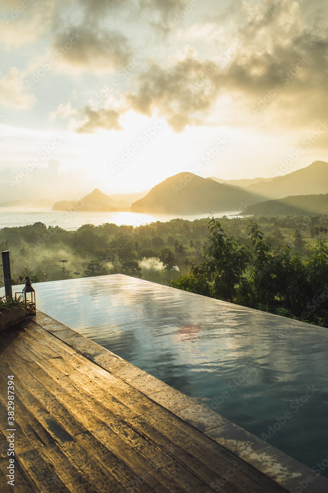 Infinity pool with amazing mountain and ocean view at sunset. Sun rays ...