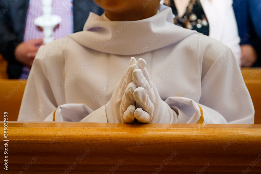 Hands of a praying child during the liturgy in the Catholic Church. The ...