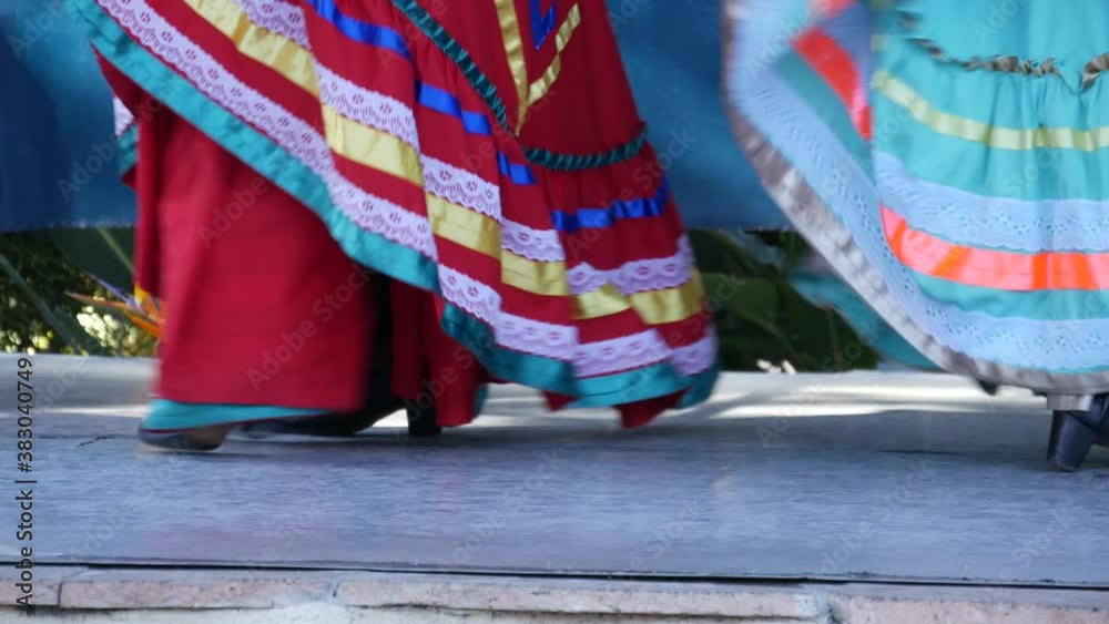 Latino women in colourful traditional dresses dancing Jarabe tapatio, mexican national folk hat ...