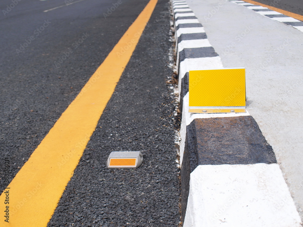 Reflector on median strip. Yellow road markings and concrete curb ...