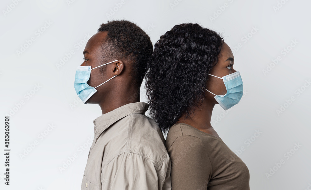 Black couple wearing protective face masks standing back to back Stock ...