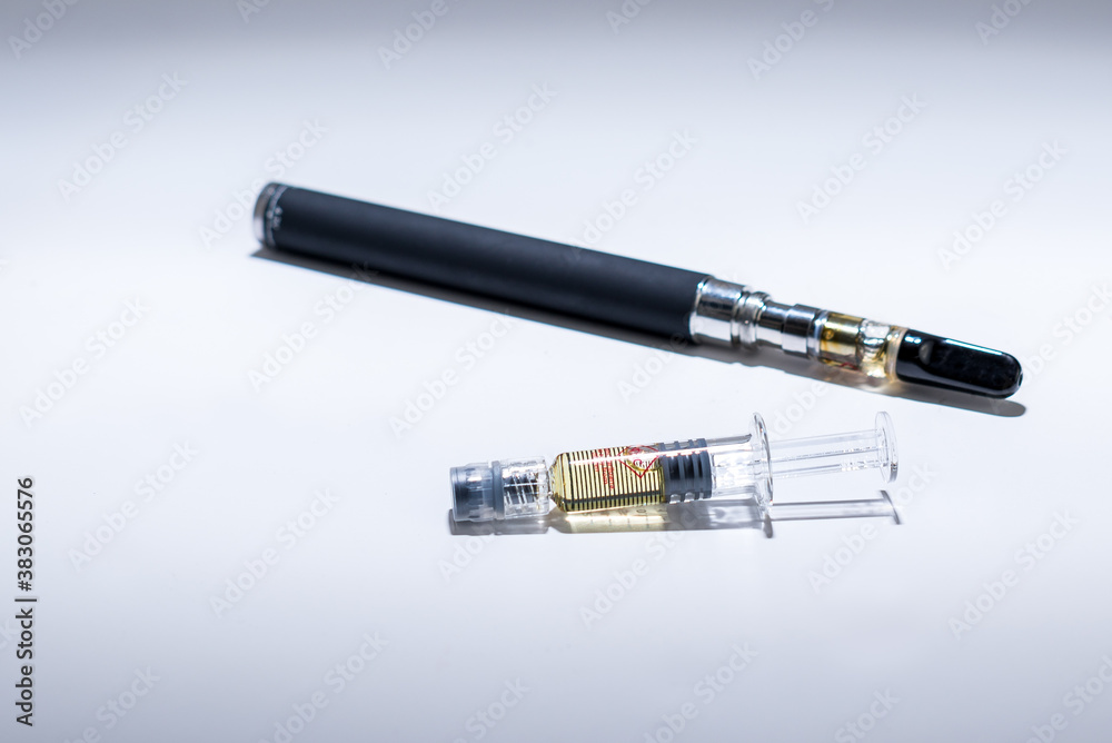 THC vaporizer pen with extract refill syringe on white surface ...