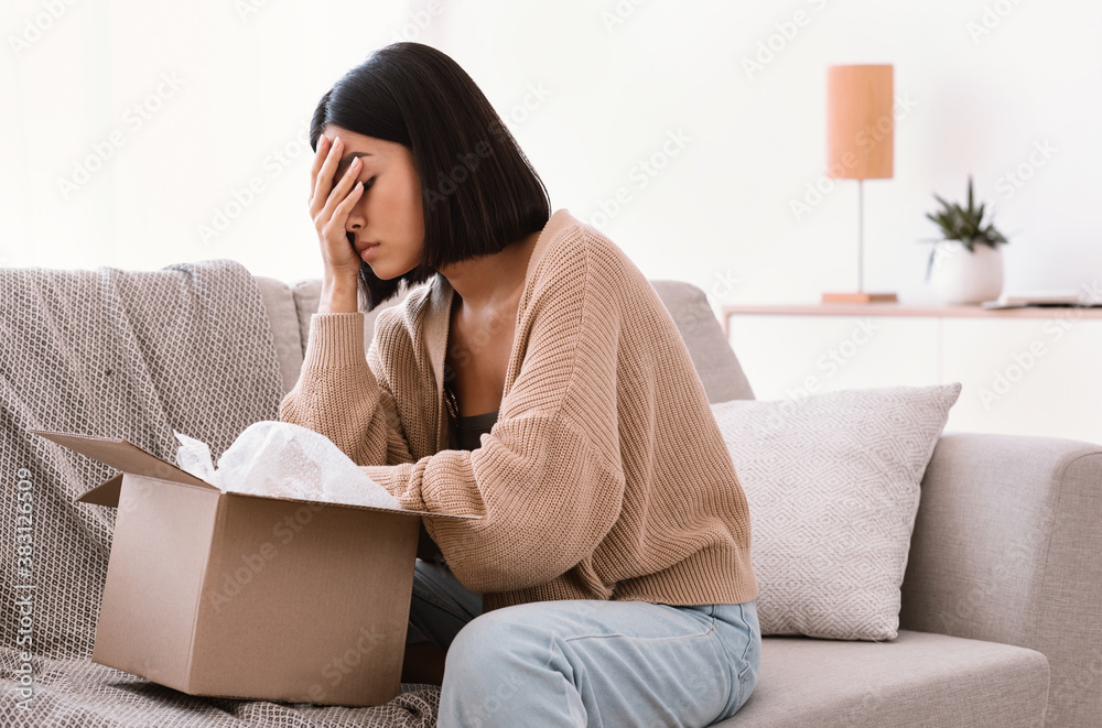 Sad young lady unpacking wrong parcel, delivery mistake Stock Photo ...