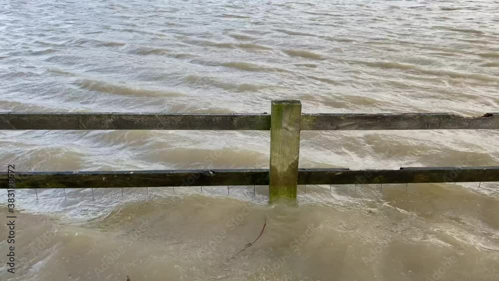 Fence around a farm field partly submerged by flood waters after a ...