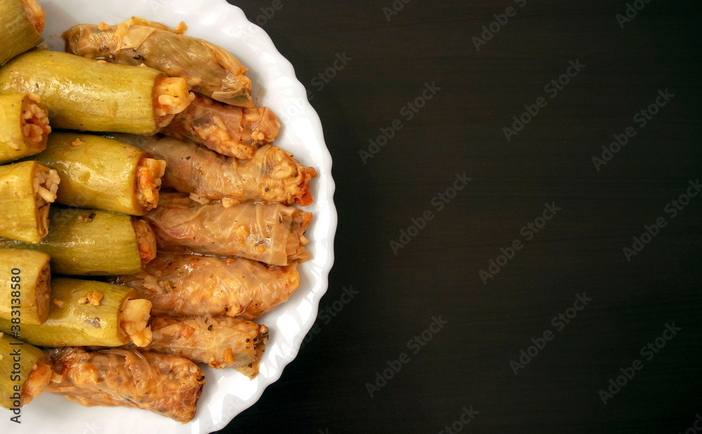 Traditional stuffed squash and cabbage rolls on white plate on dark ...