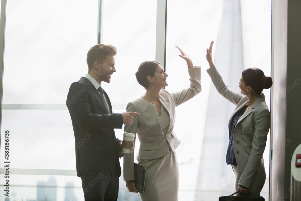 Corporate business people high-fiving in office window Stock Photo ...