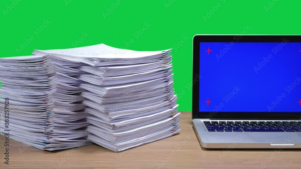 Blue screen laptop computer and Stacks overload document paper files on ...