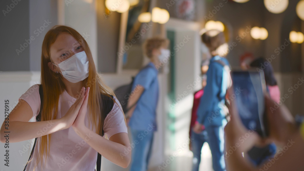 Students filming on smartphone camera dancing classmate in safety mask ...