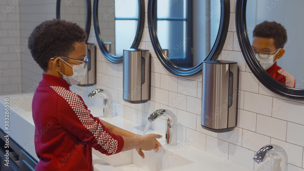 African student in safety mask washing hands in modern school restroom ...