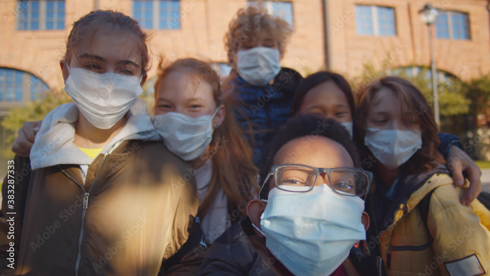 Multiethnic school children wearing protective face masks taking selfie ...