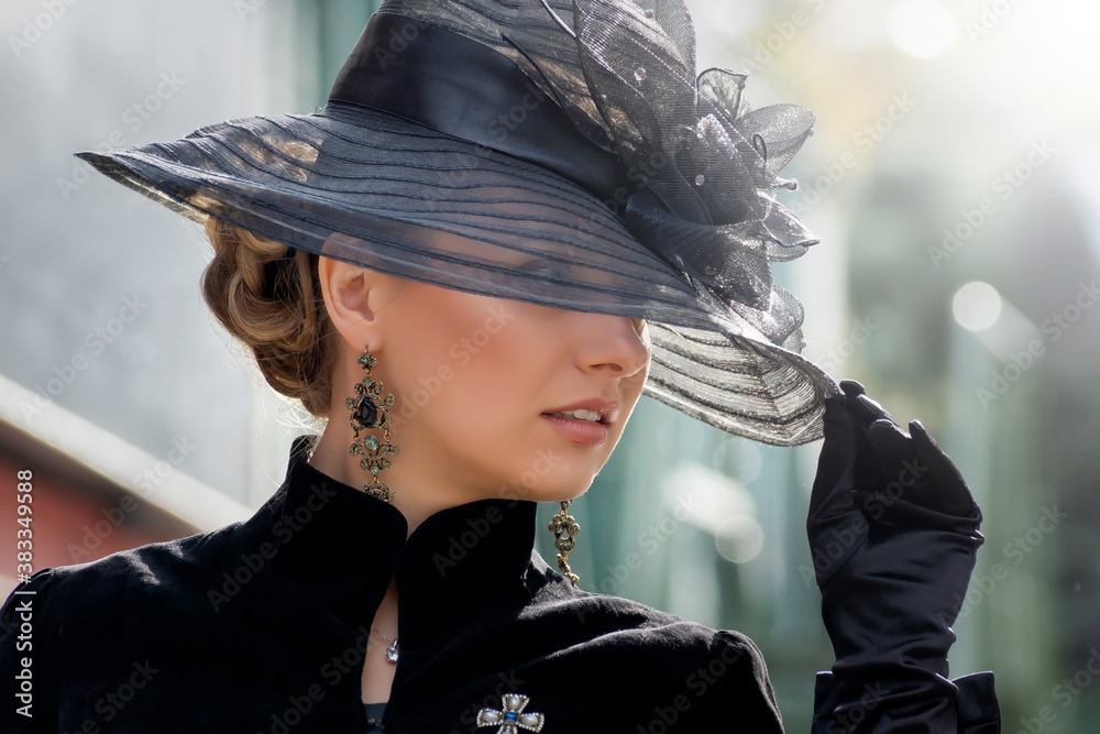 Steampunk girl in a black dress and hat near an old steam locomotive ...