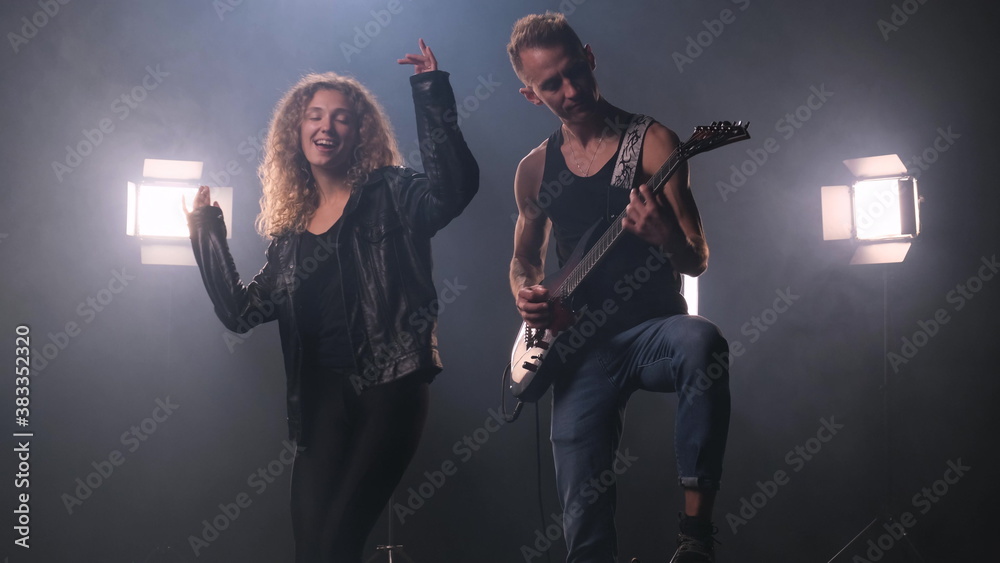 Two rock stars are dancing on stage. The guy in the black T-shirt plays ...