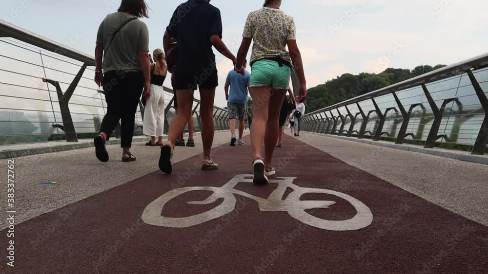 People walk along the pedestrian bike path, bottom and back view. A ...